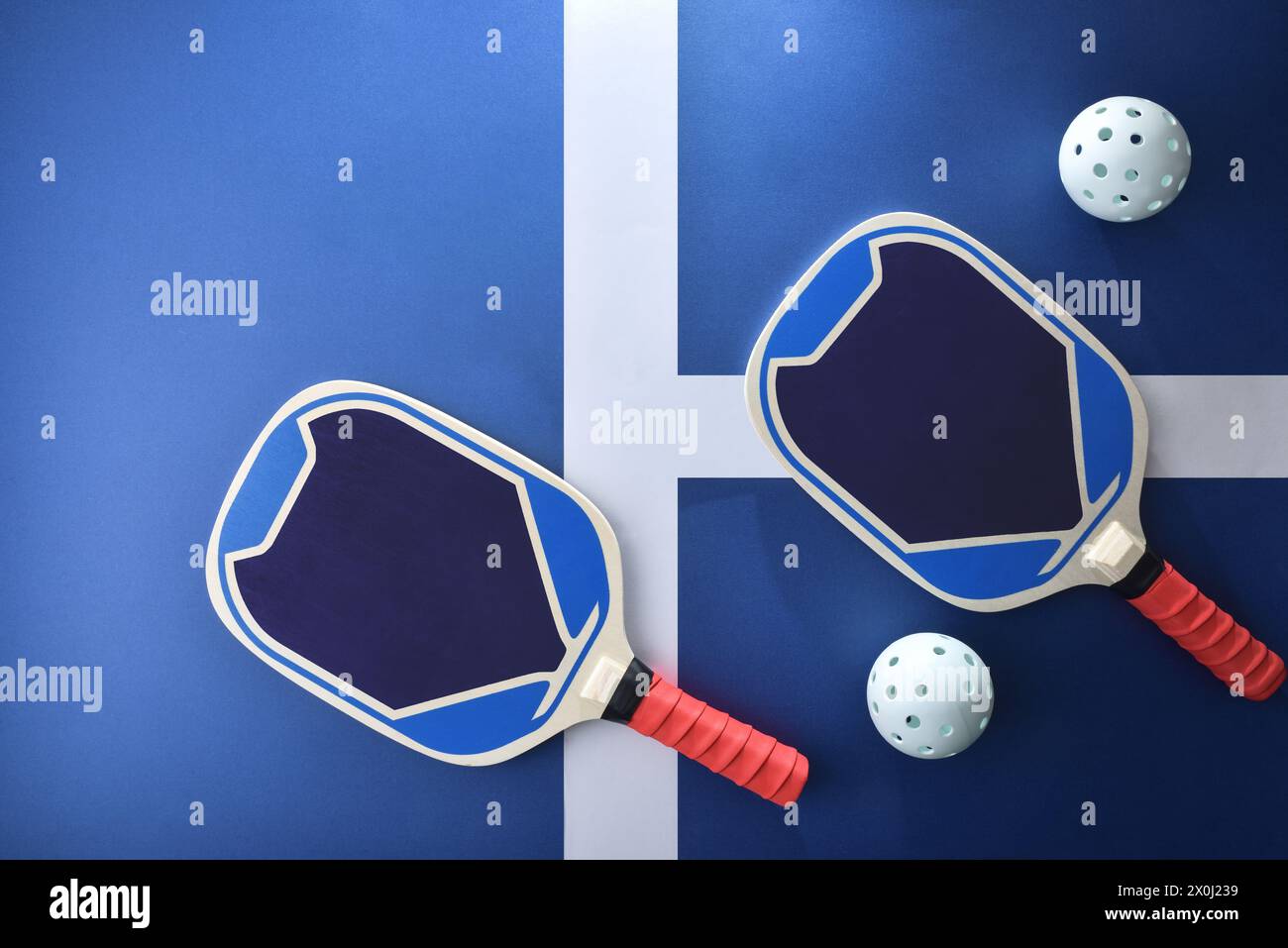 Blue and red wooden pickleball paddles and a white balls on blue ...