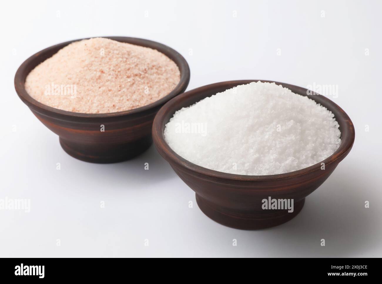 Different types of natural salt in bowls on white background Stock ...