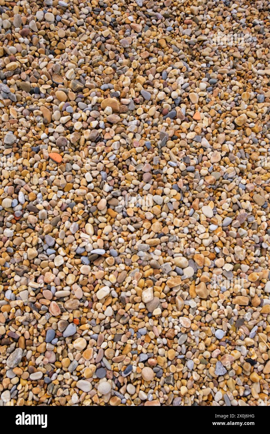 A collection of assorted rocks lie scattered on the wet pebbled ground ...