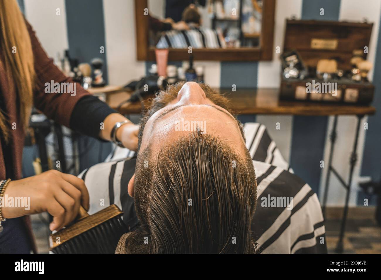 Man enjoys luxurious haircare at upscale barber shop. Female barber ...