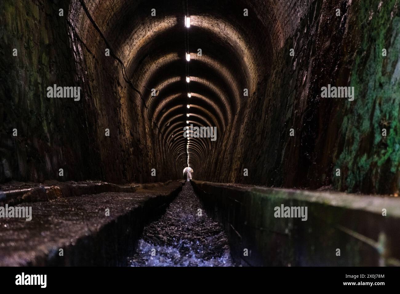 long tunnel, illuminated by artificial lights, surrounded by walls on ...