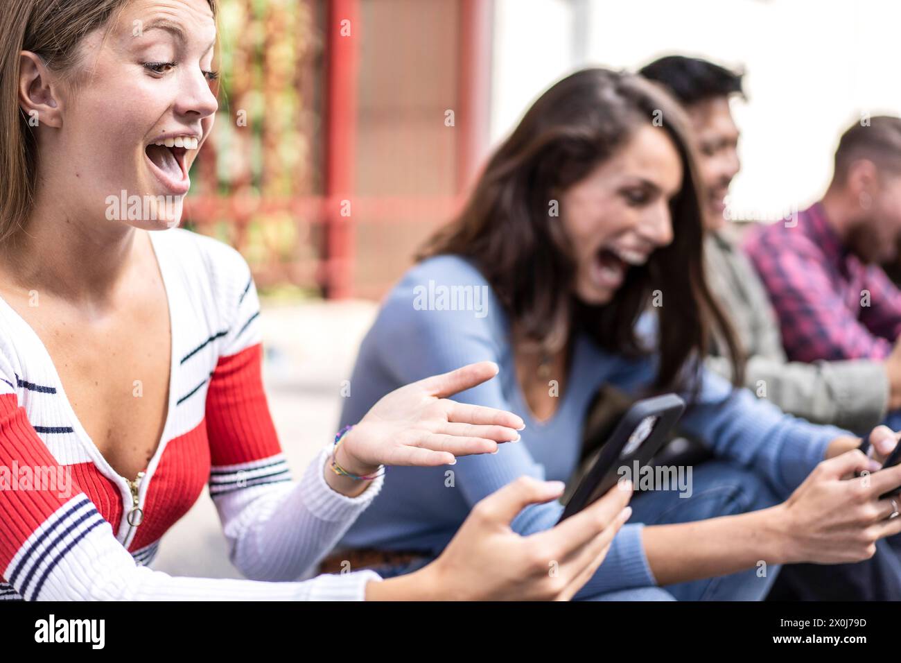 Young friends laughing at content on smartphone. Urban gen z sharing a ...