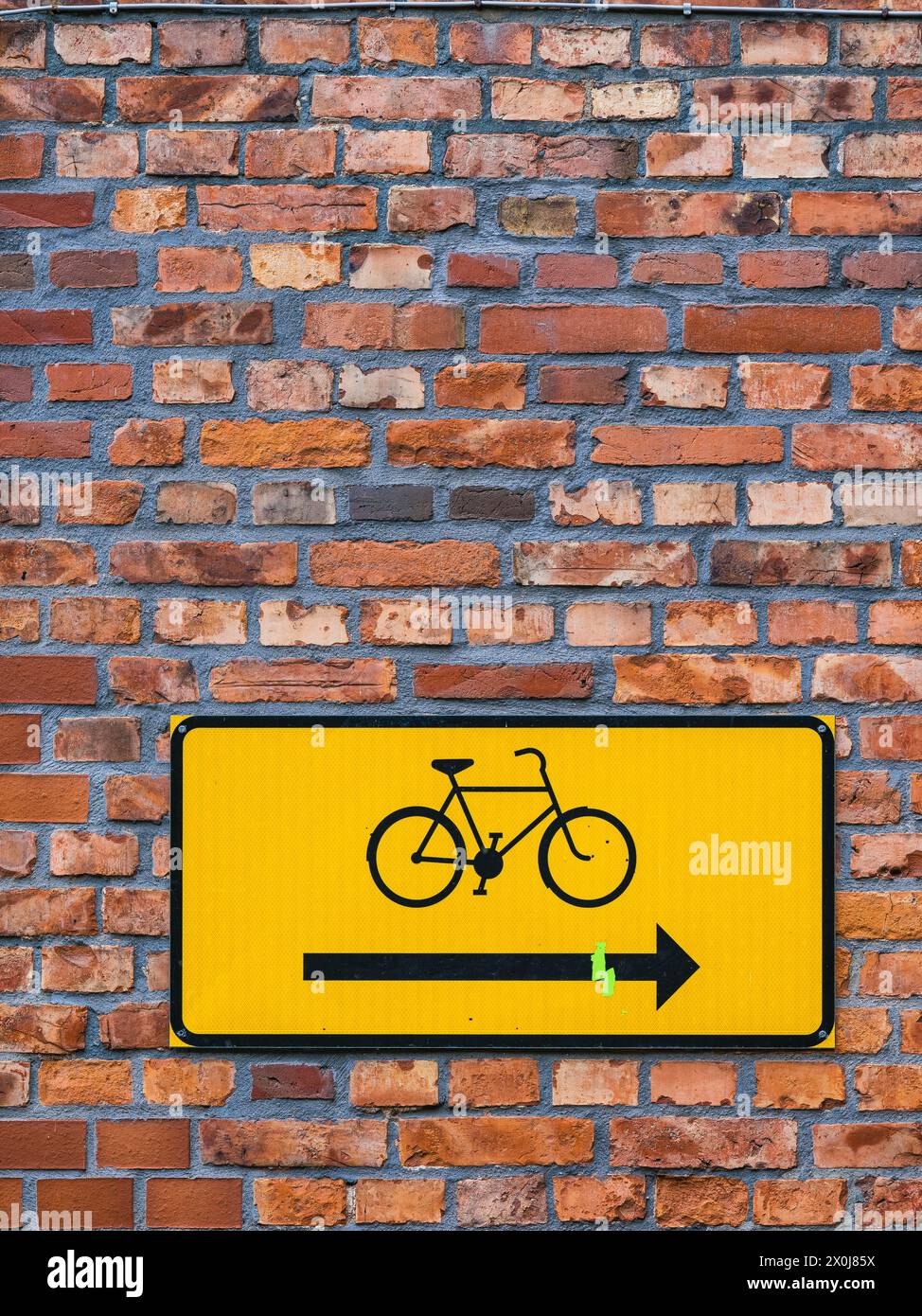 A yellow sign with a bicycle symbol painted on it is attached to a ...