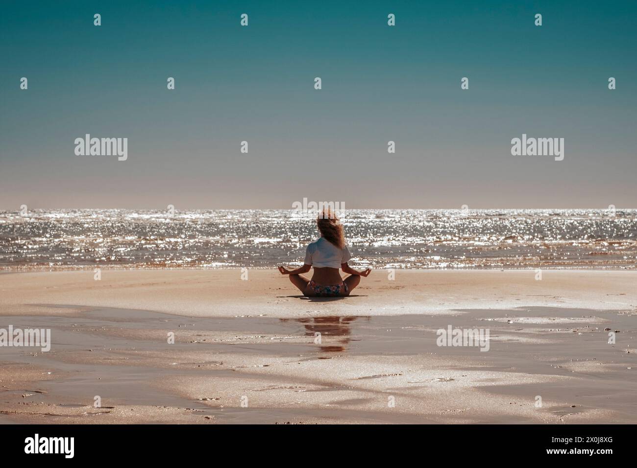 Inner balance life concept with woman sitting at the beach doing yoga ...