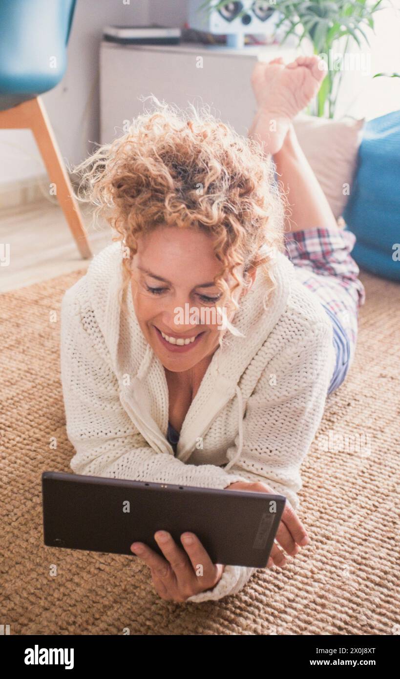 Woman laying at home on the carpet floor and use laptop device with ... Woman laying at home on the carpet floor and use laptop device with ...