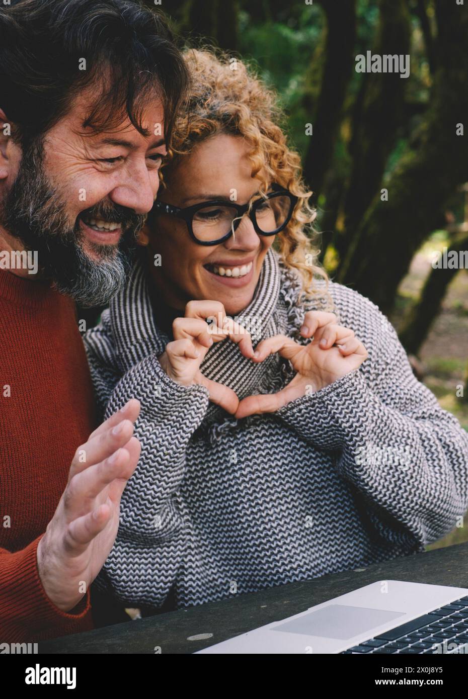 Cheerful adult couple have fun in video call connection using laptop ...