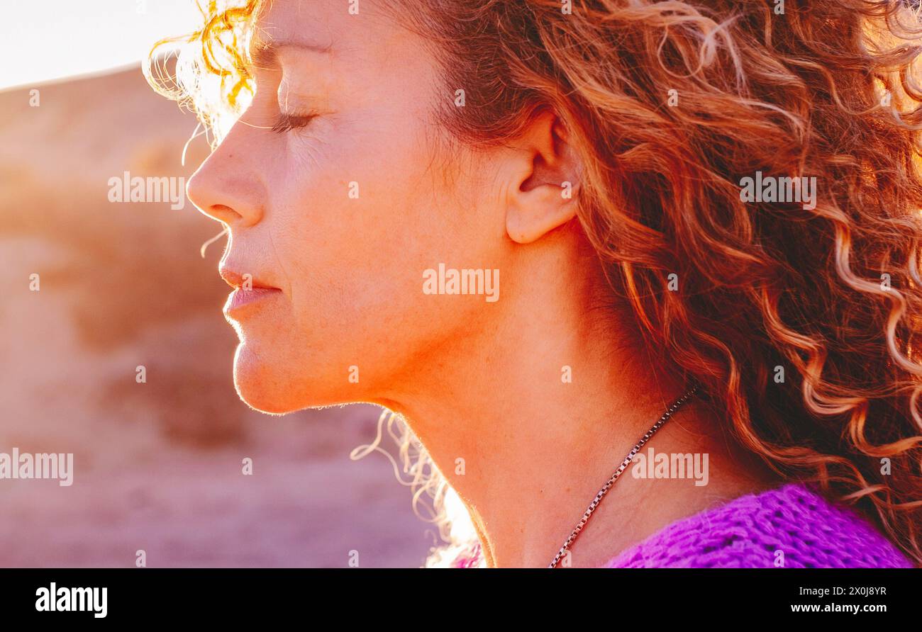 Close up sunset portrait of attractive woman with closed eyes and sun ...