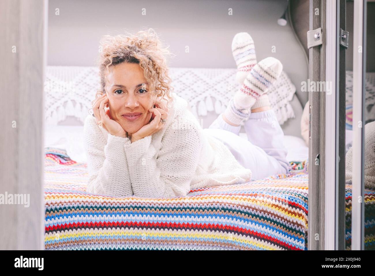 Portrait of cheerful pretty adult woman laying and smiling inside her ...
