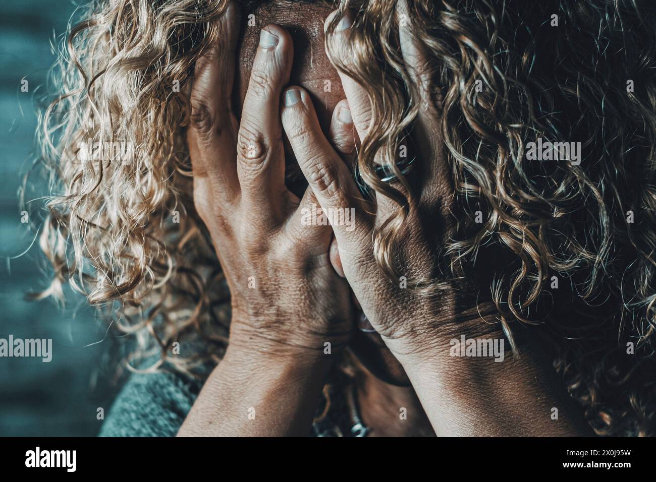 Close up of desperate woman with hands on face in the dark at home ...