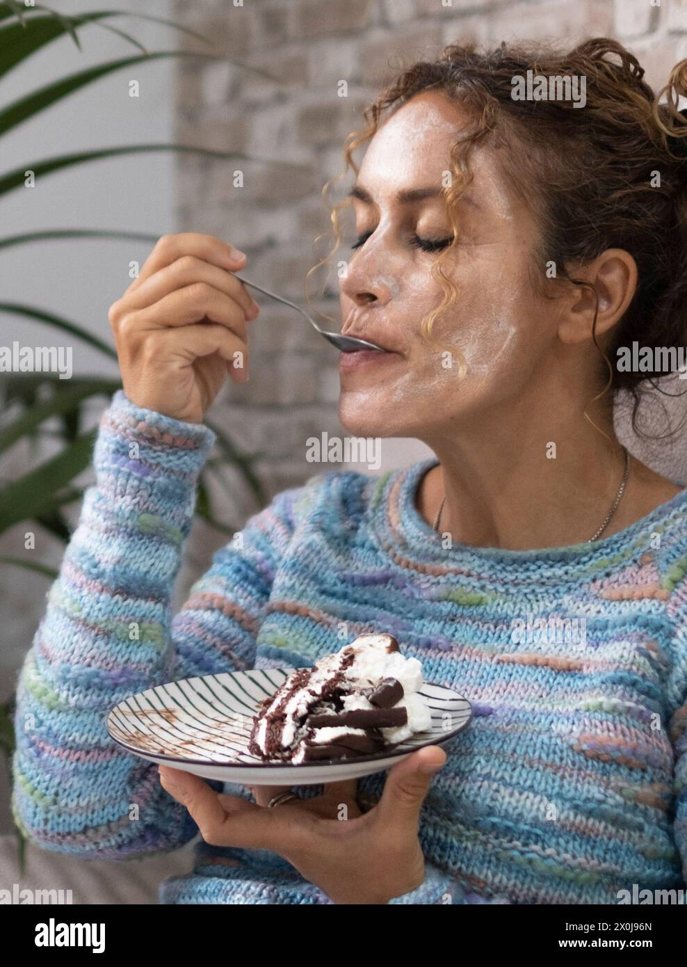 One woman at home enjoying eating tasty cake with cream and chocolate ...