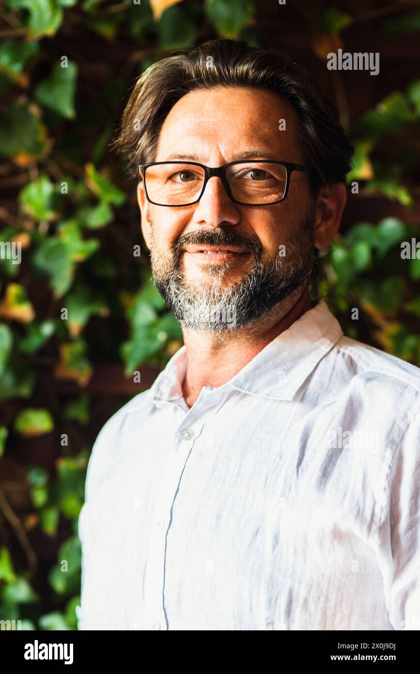 Portrait of adult mature handsome bearded man with white shirt smiling ...