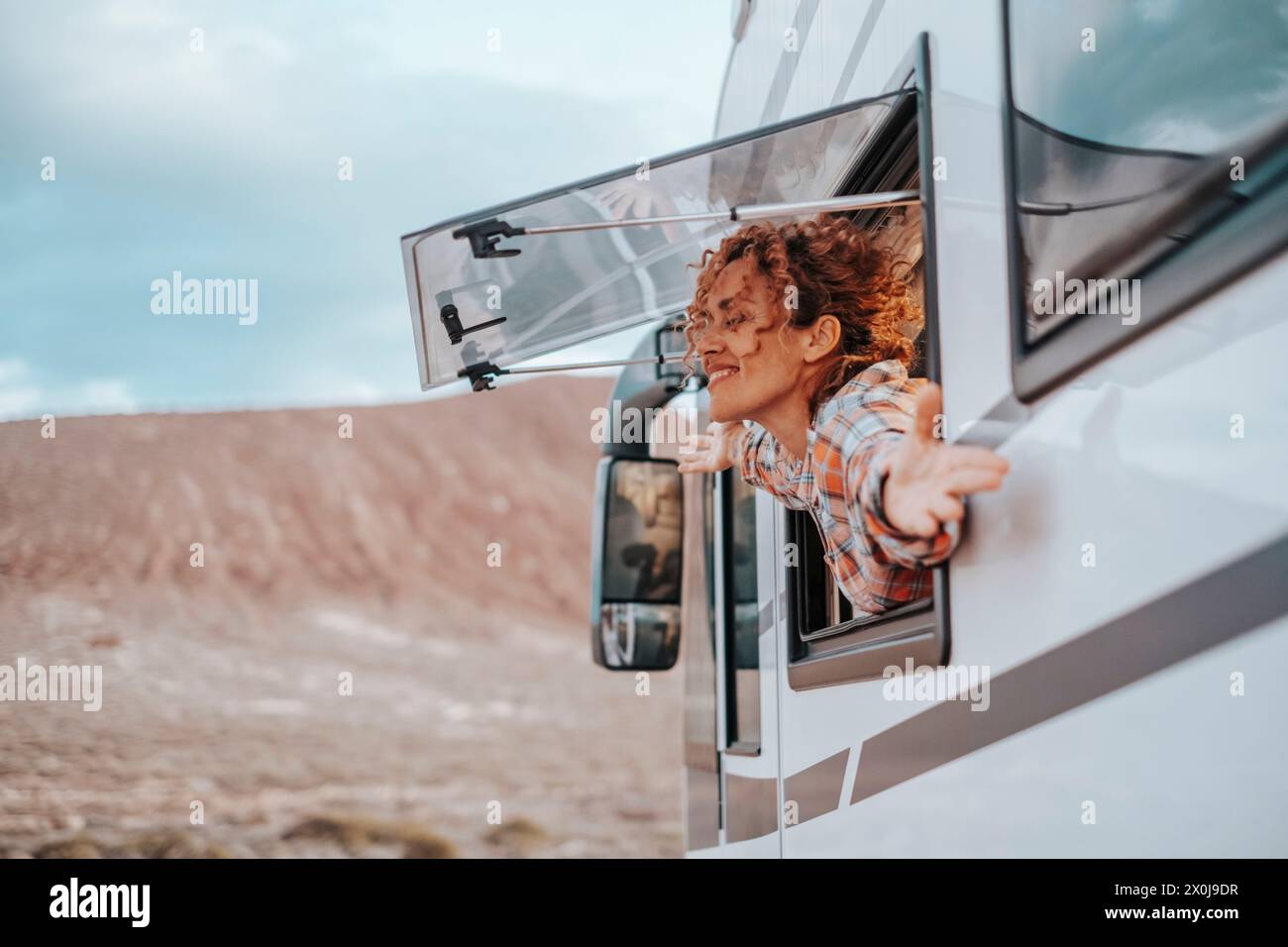 One happy traveler lady outside the window of camper van outstretching ...