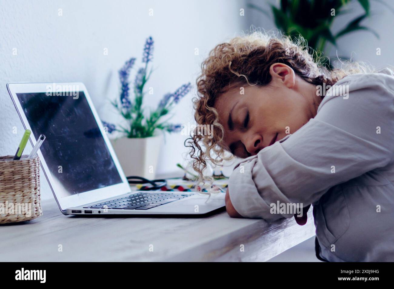 One woman asleep in front of an open laptop in home office workplace ...