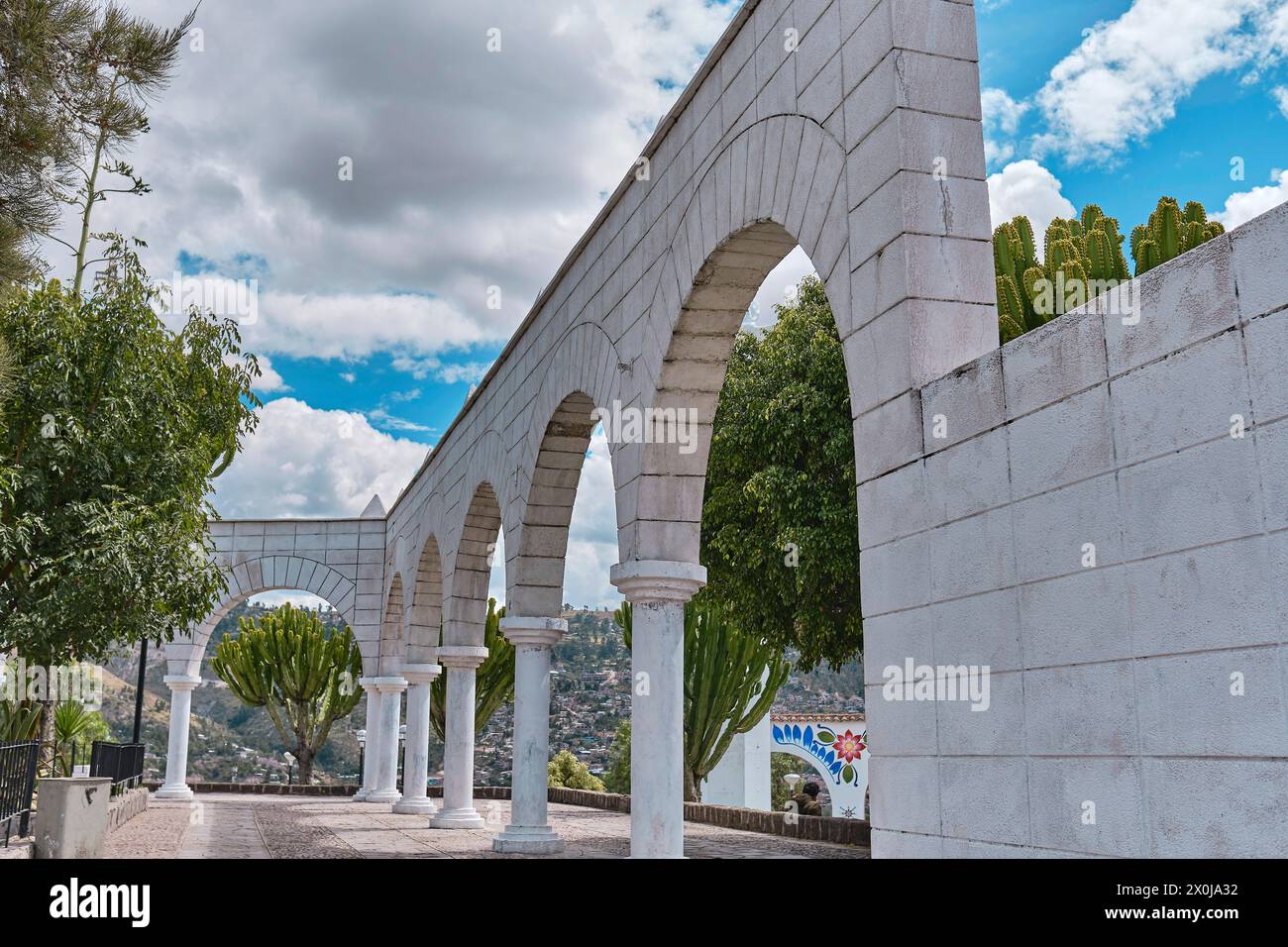 A long white archway with trees on either side, arch of Acuchimay ...