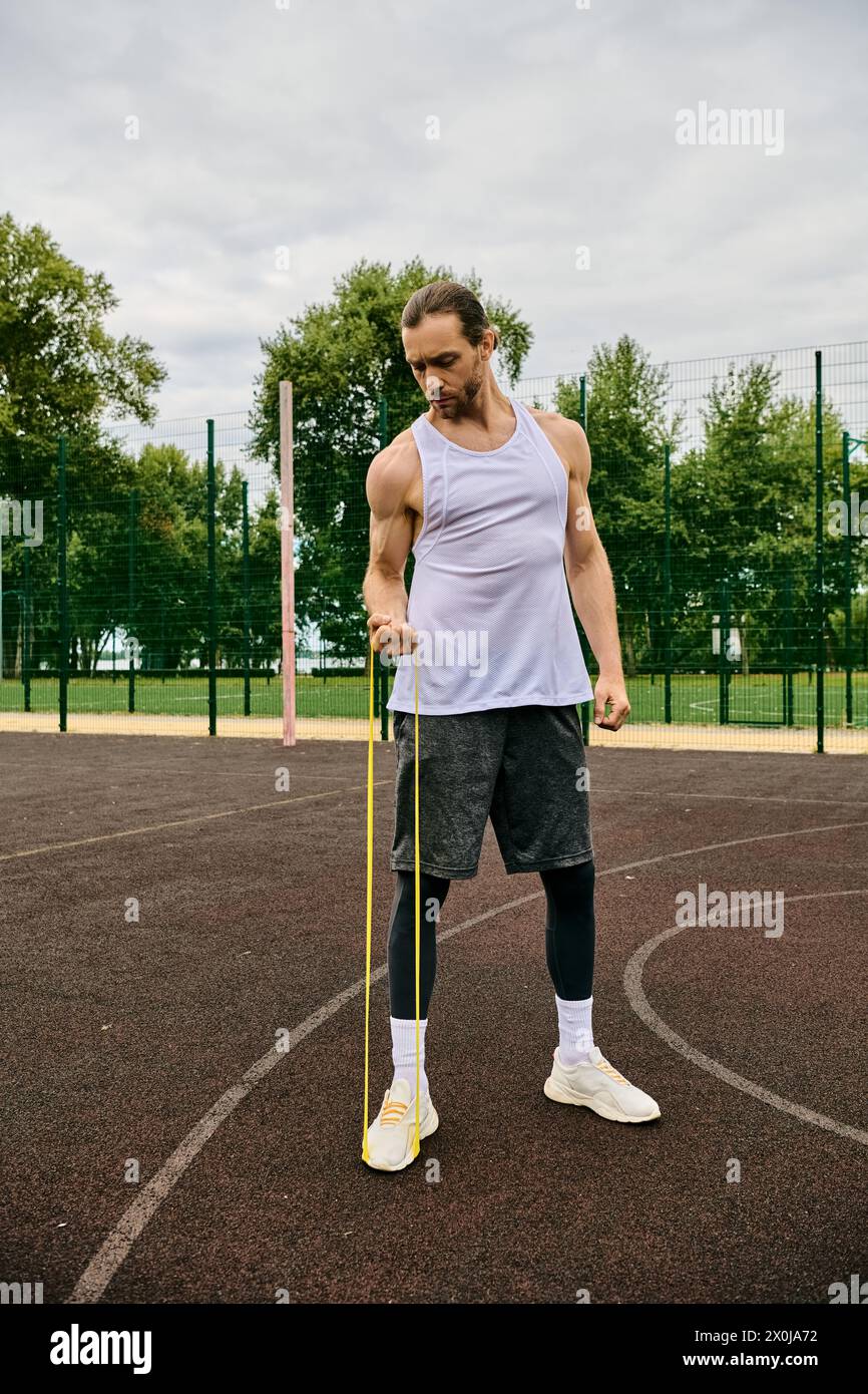 A determined man stands on the court, holding a yellow elastics while ...