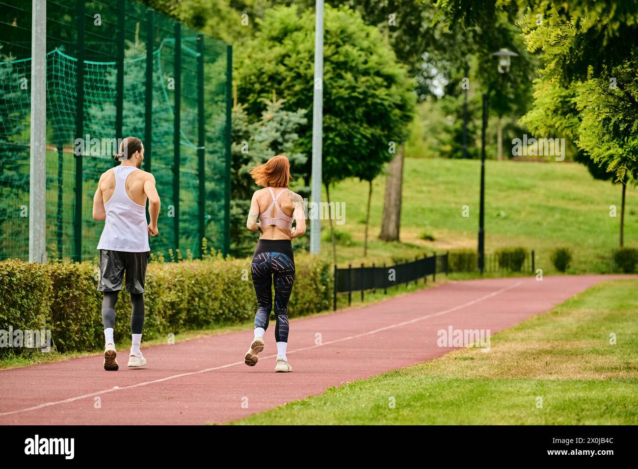 A man and woman in sportswear are running down a path with ...