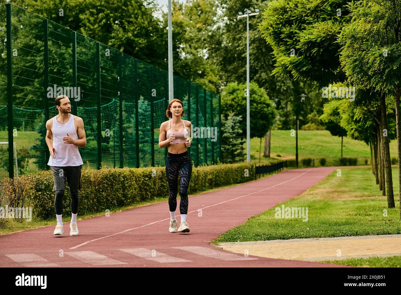 A couple in sportswear, energetically running down a path, showing ...