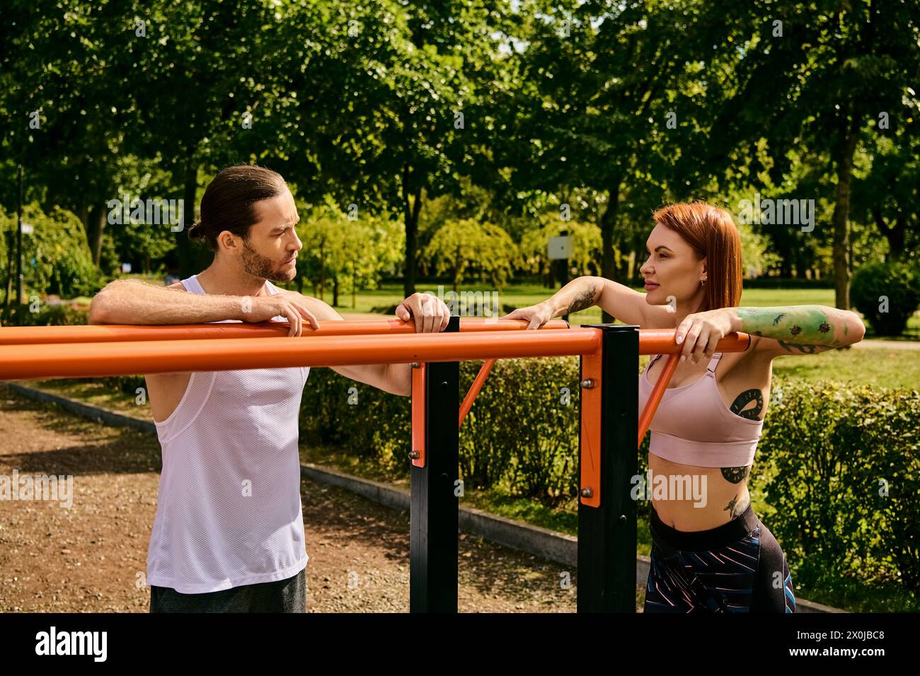 A man and a woman in sportswear stand side by side outdoors, focusing ...