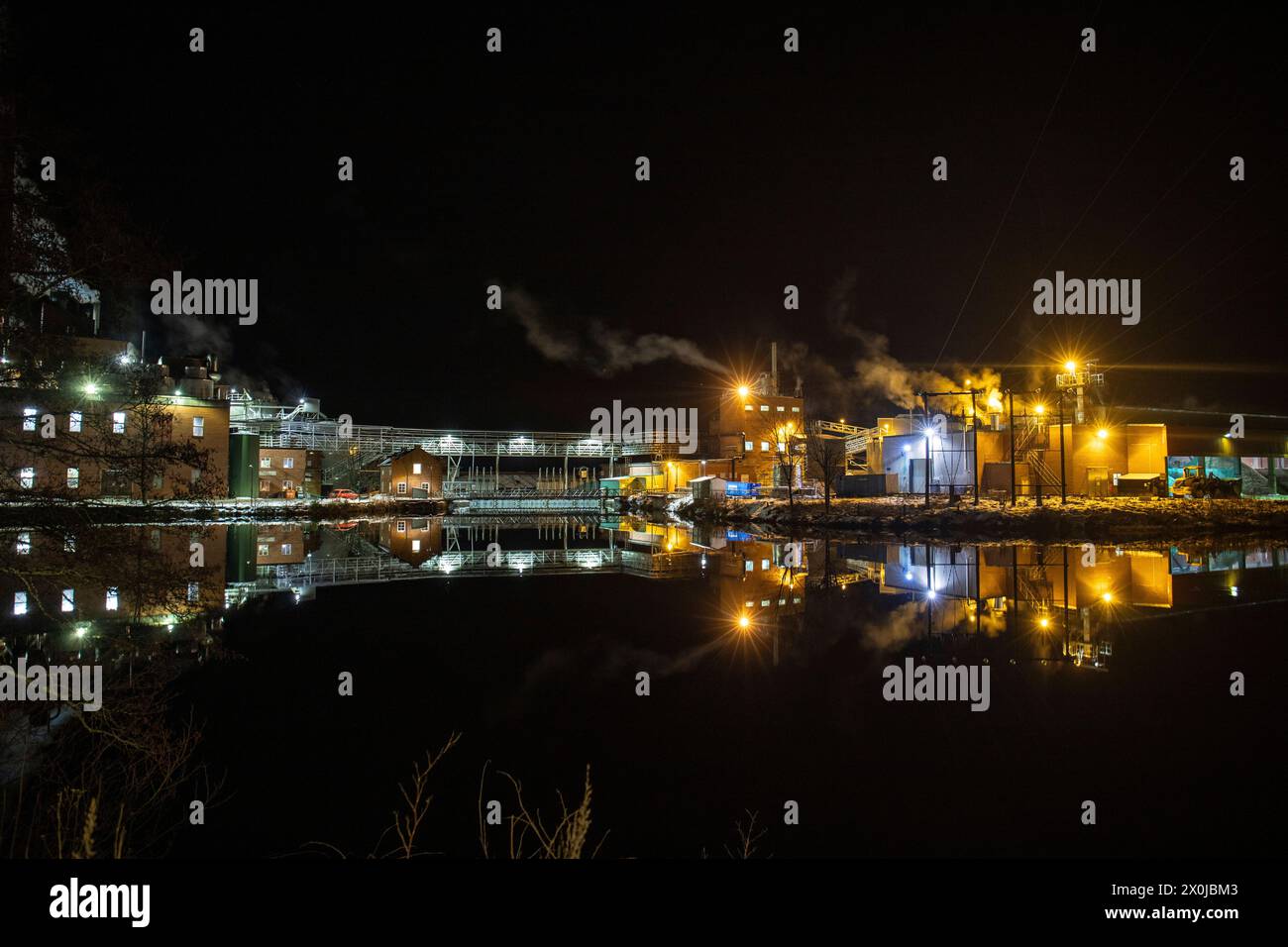 Paper factory at night. Winter photo of a small factory with reflection ...