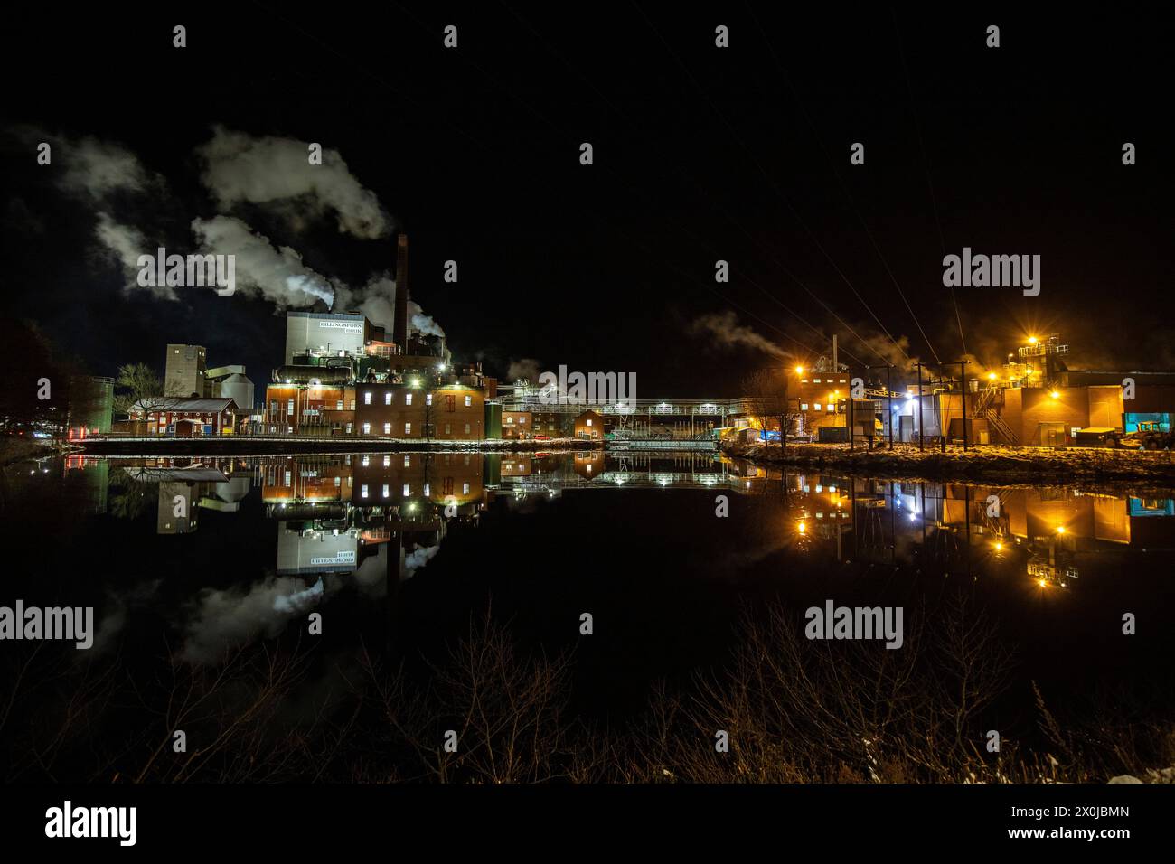 Paper factory at night. Winter photo of a small factory with reflection ...