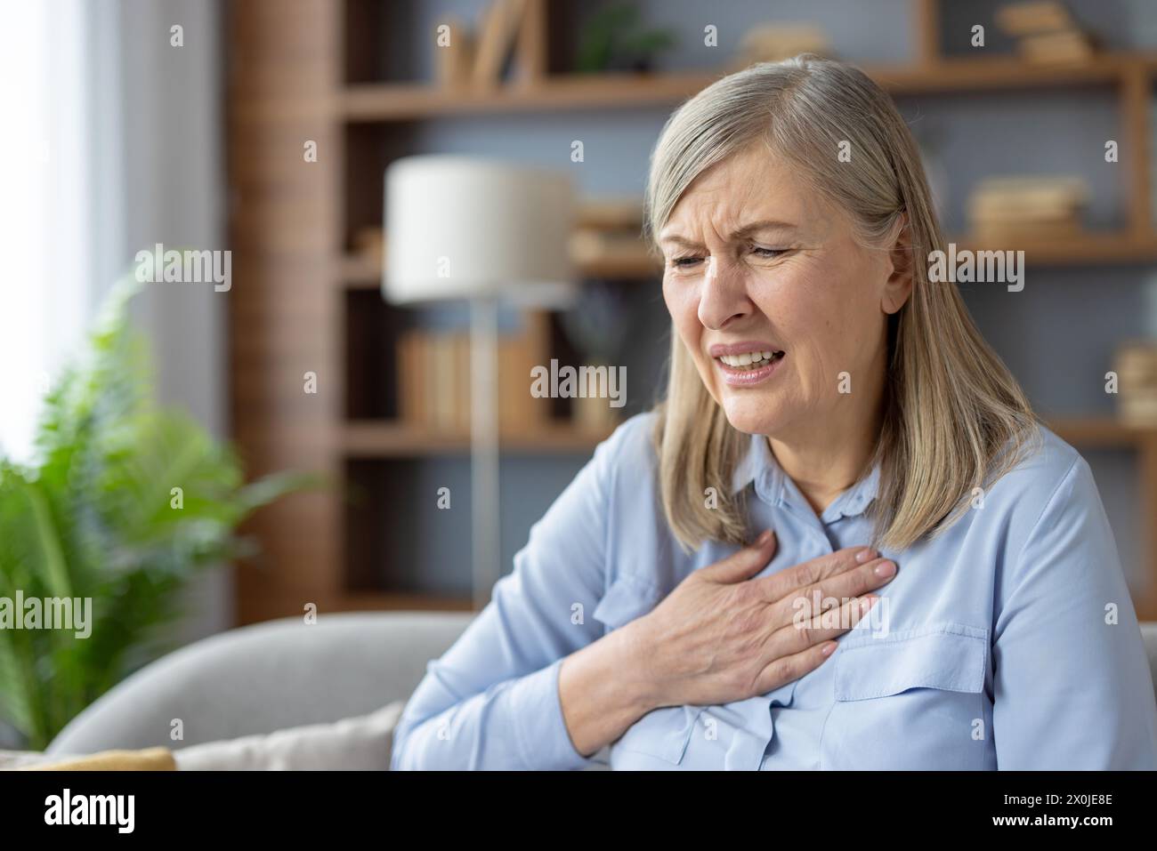 Elderly woman feeling acute chest pain, holding her chest with a pained ...