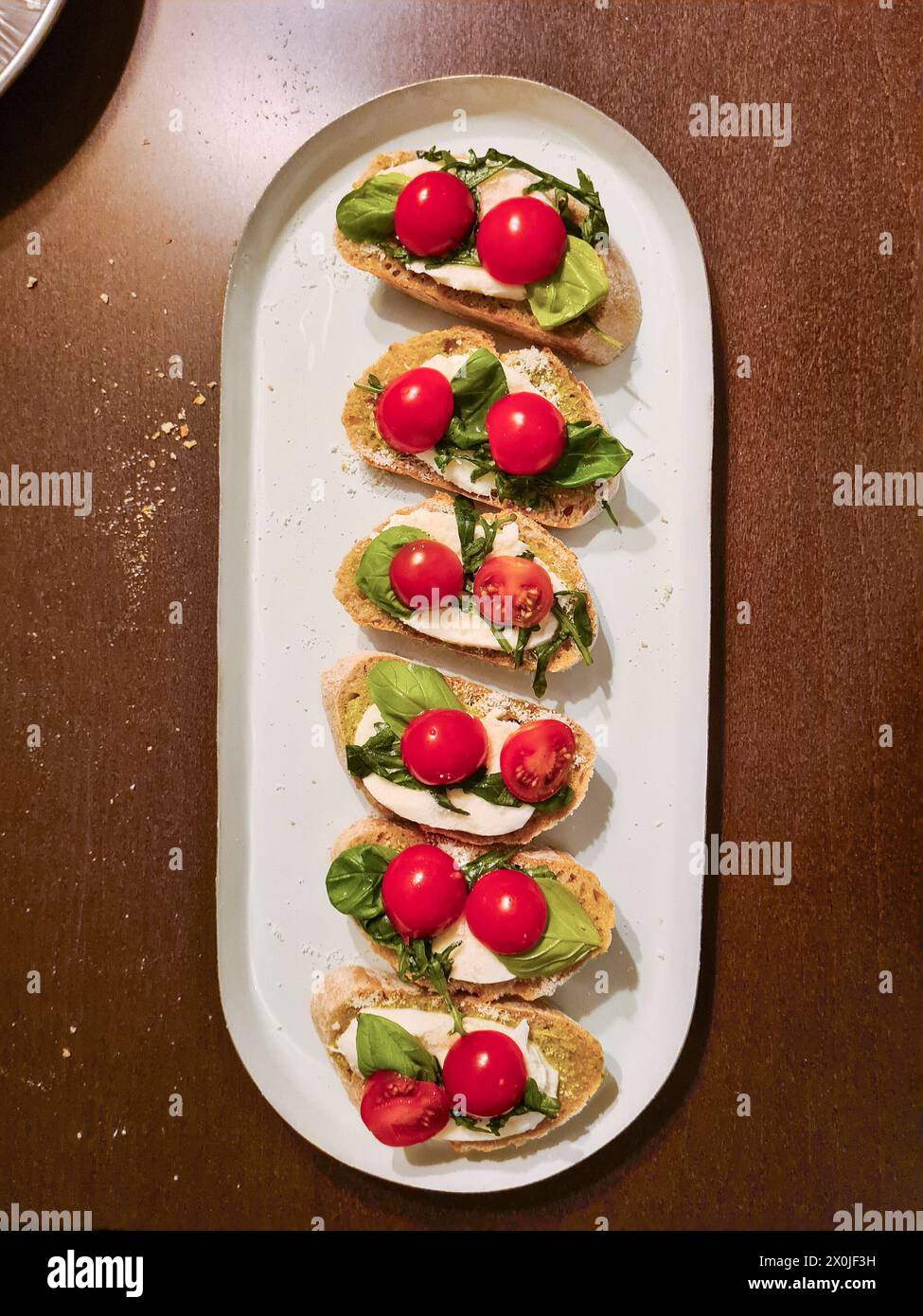 Serving platter with whole cocktail tomatoes and mozzarella on sliced ...