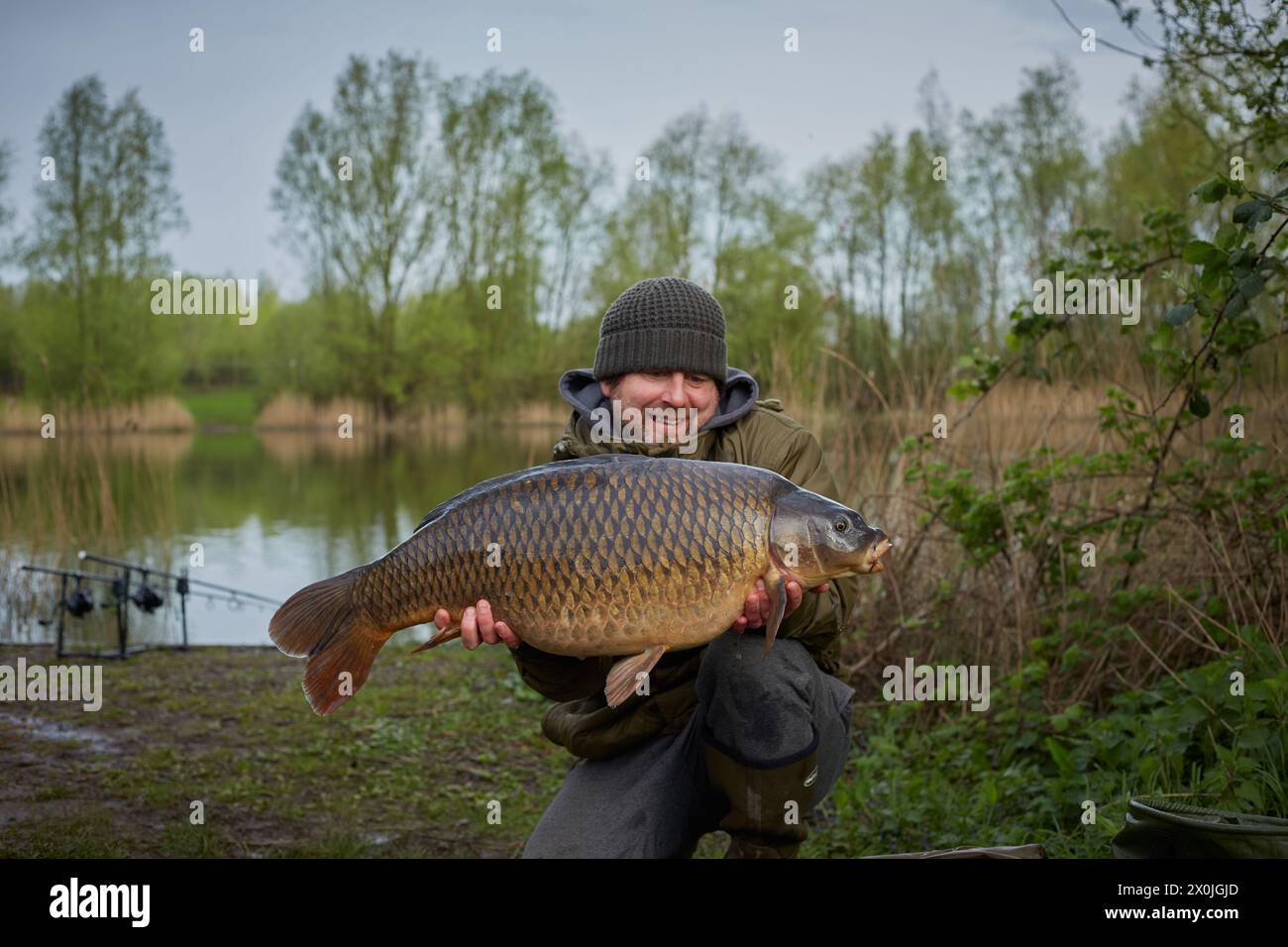 Fisherman holding up a common carp with a lake landscape in the ...