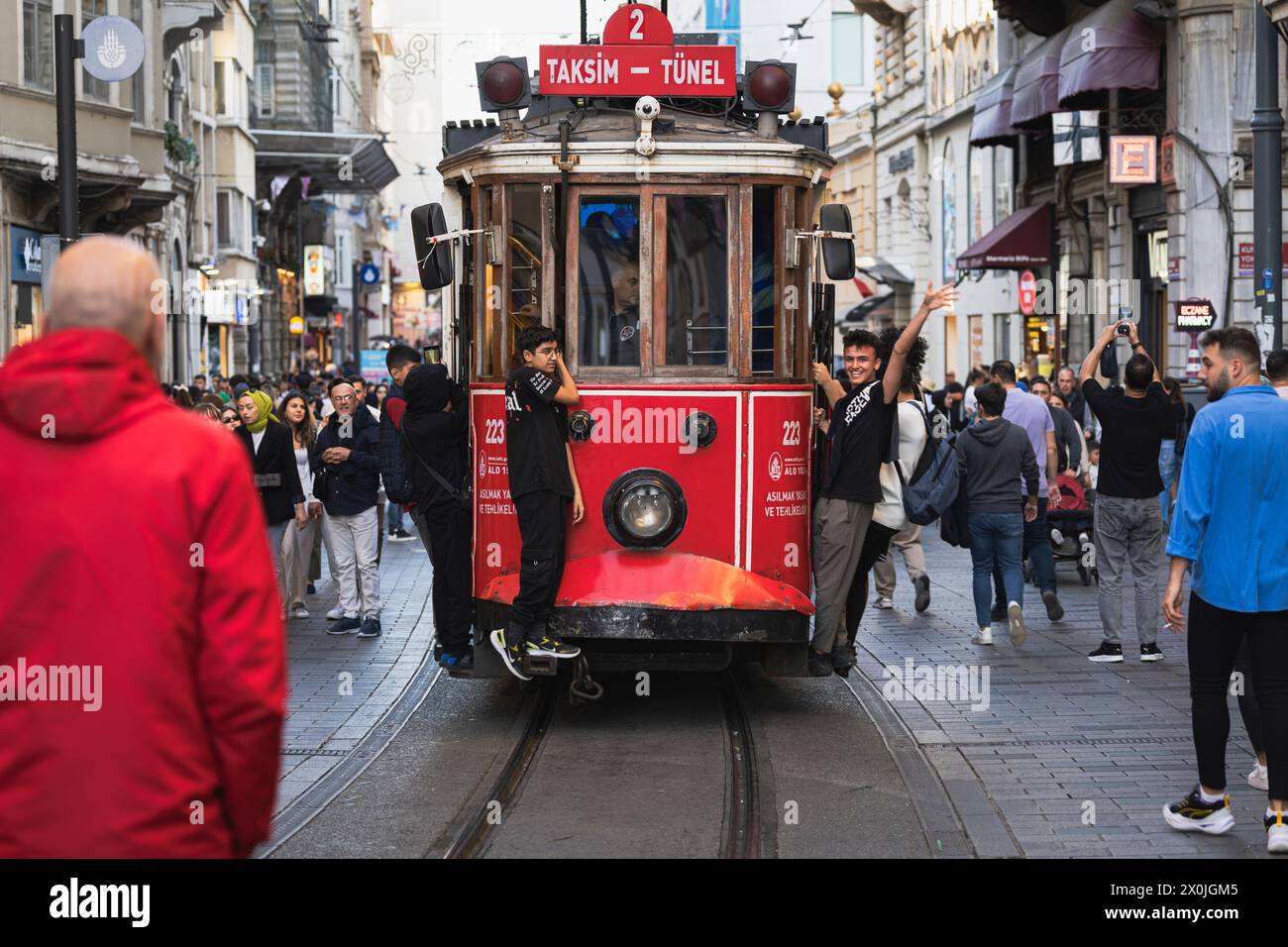 Young people riding on the outside of a historic streetcar, shopping ...