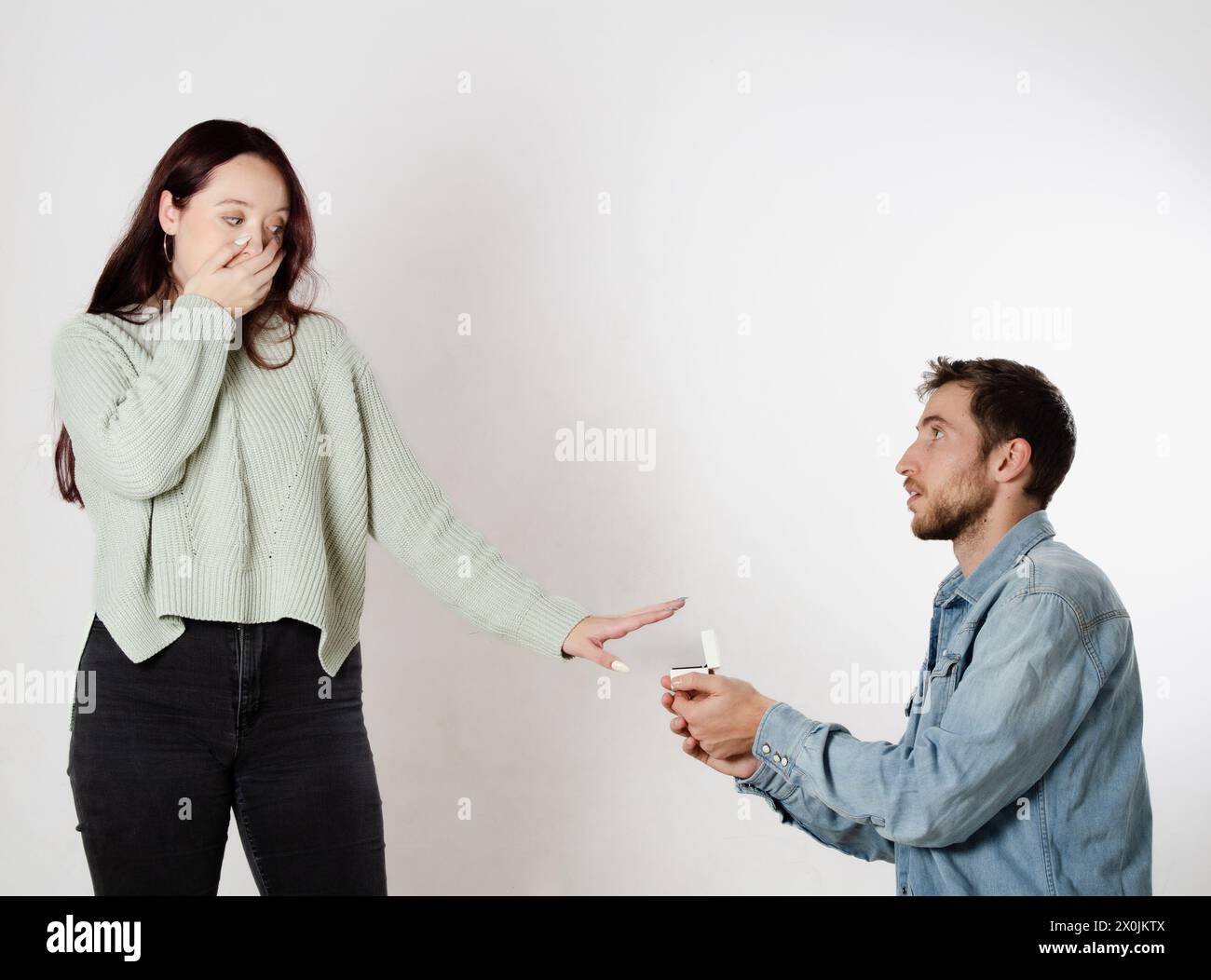 Man on his knees proposing marriage to his girlfriend with a ring box ...