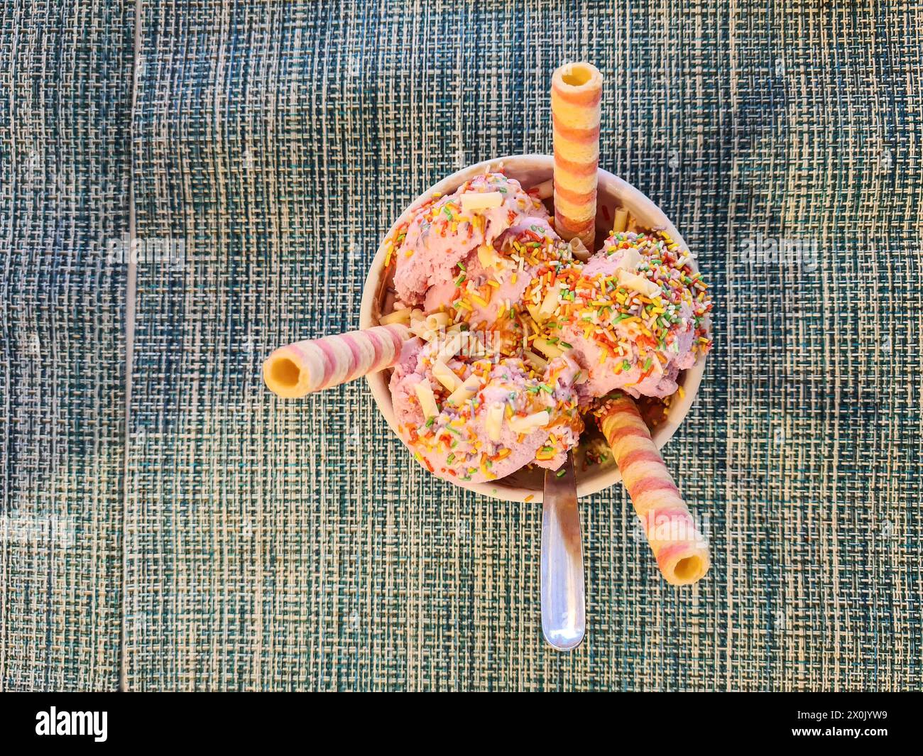 A colorful ice cream sundae with three scoops of strawberry ice cream ...