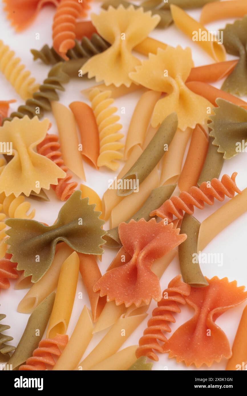 Tricolor macaroni of different types. It is located on a white surface ...