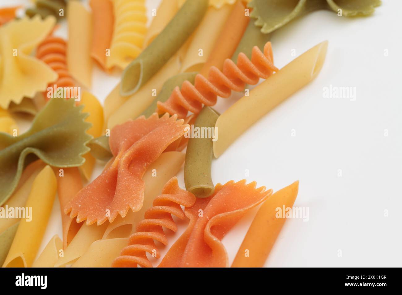 Tricolor macaroni of different types. It is located on a white surface ...