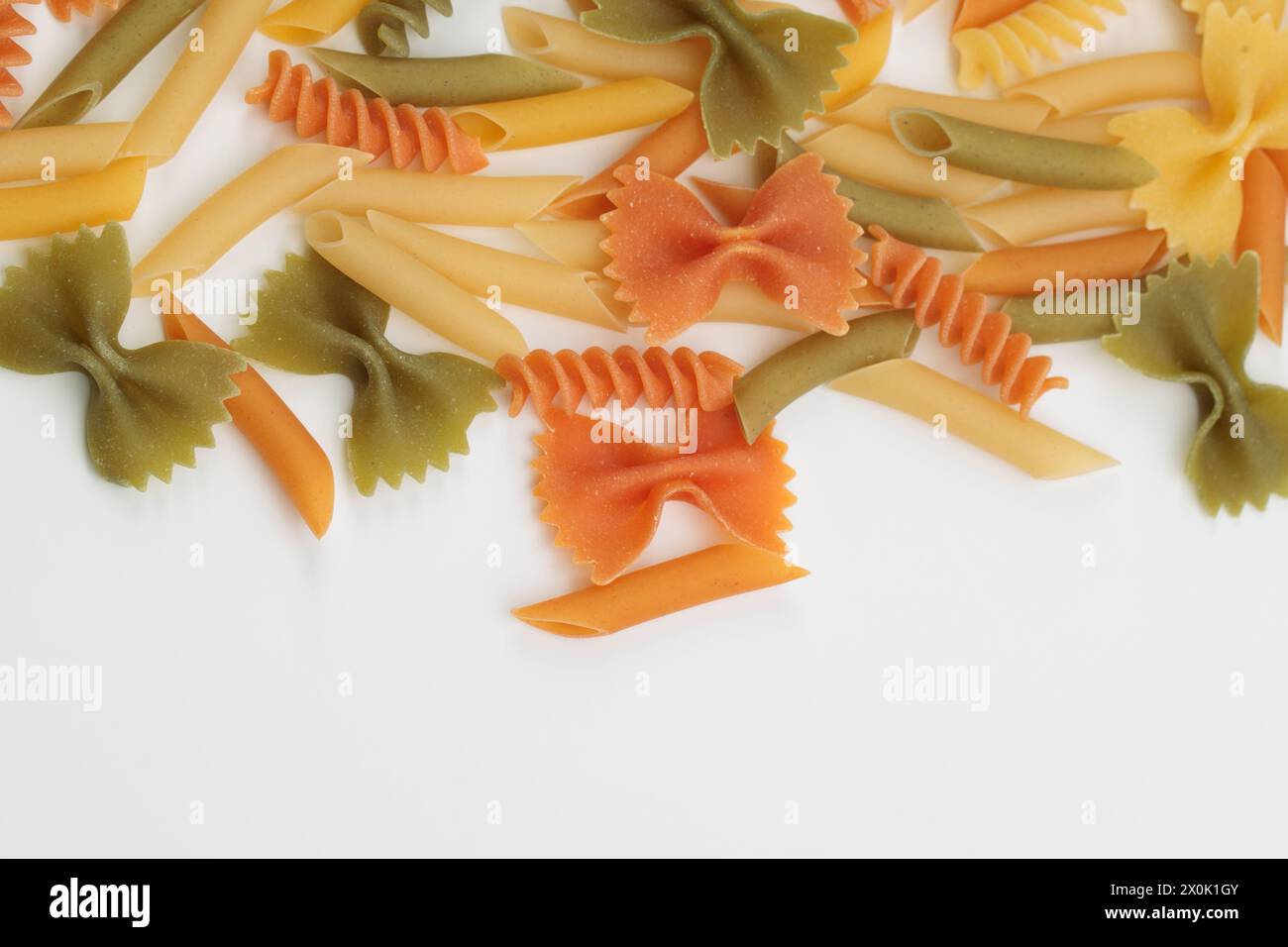 Tricolor macaroni of different types. It is located on a white surface ...