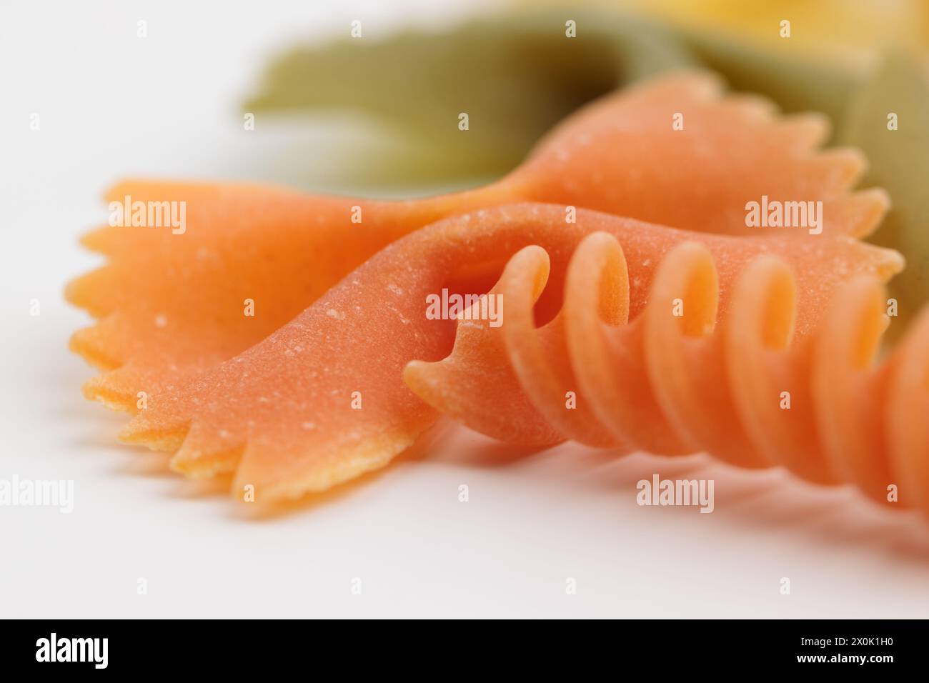 Tricolor macaroni of different types. It is located on a white surface ...