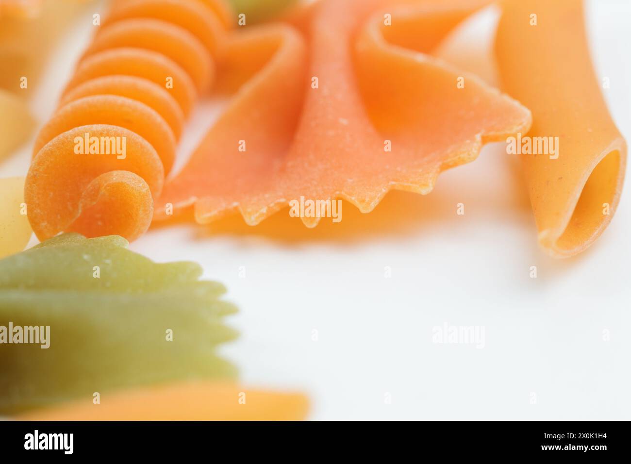 Tricolor macaroni of different types. It is located on a white surface ...