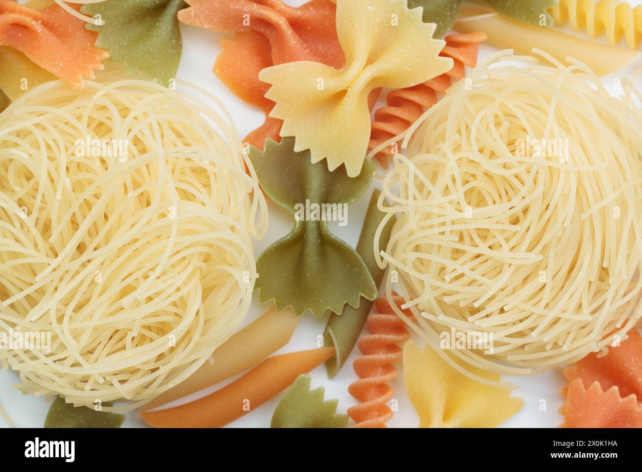 Tricolor macaroni of different types. It is located on a white surface ...