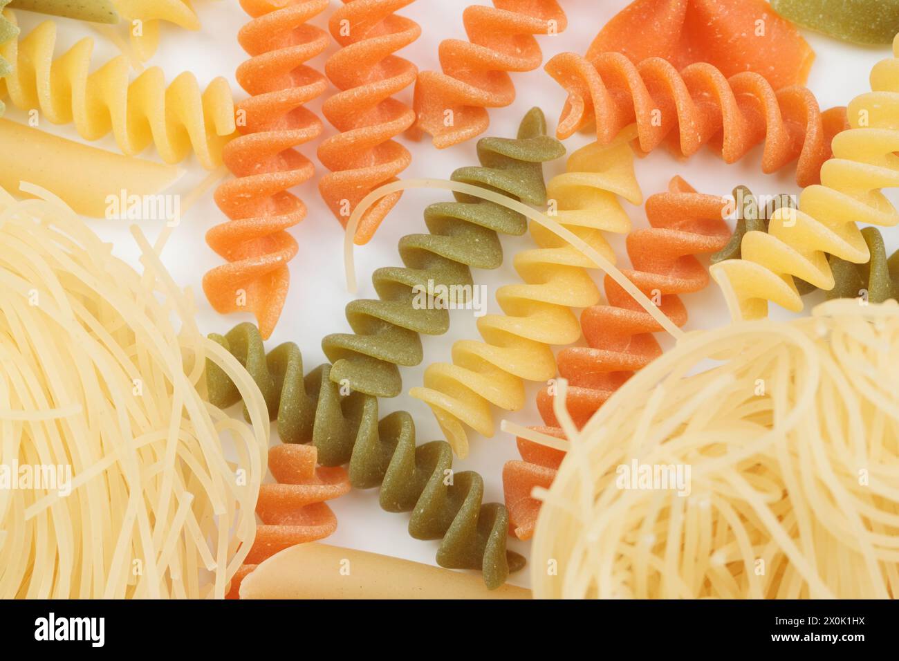 Tricolor macaroni of different types. It is located on a white surface ...