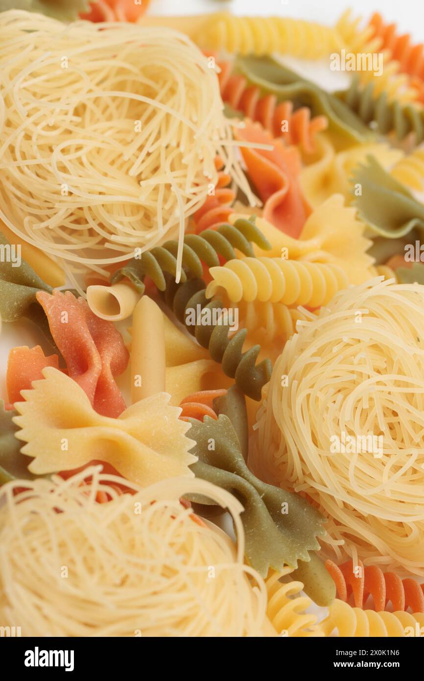 Tricolor macaroni of different types. It is located on a white surface ...