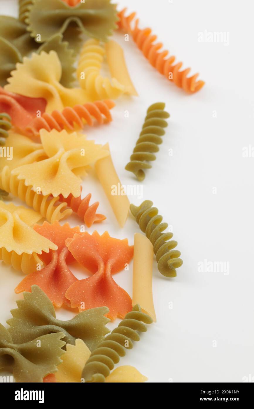 Tricolor macaroni of different types. It is located on a white surface ...