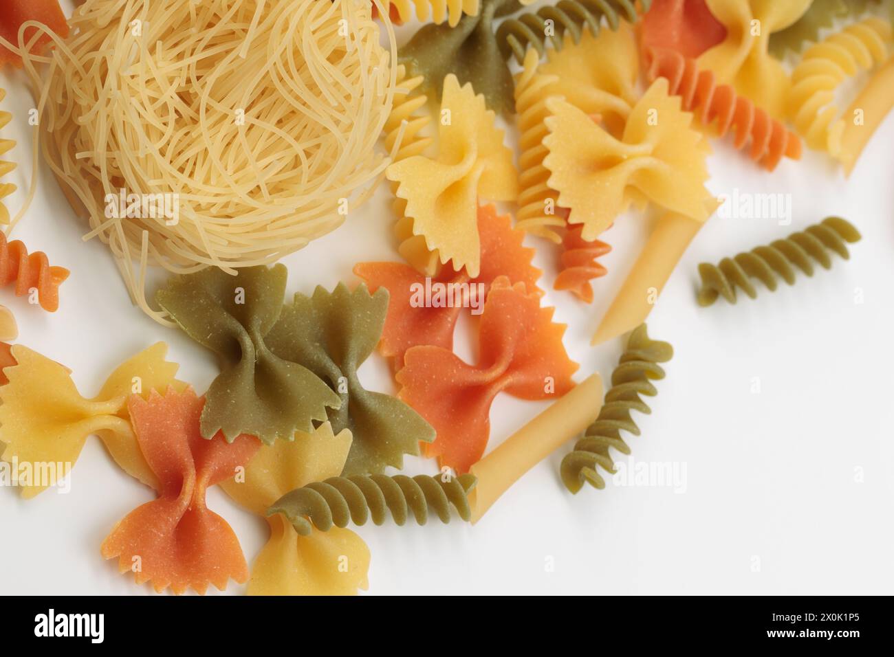 Tricolor macaroni of different types. It is located on a white surface ...