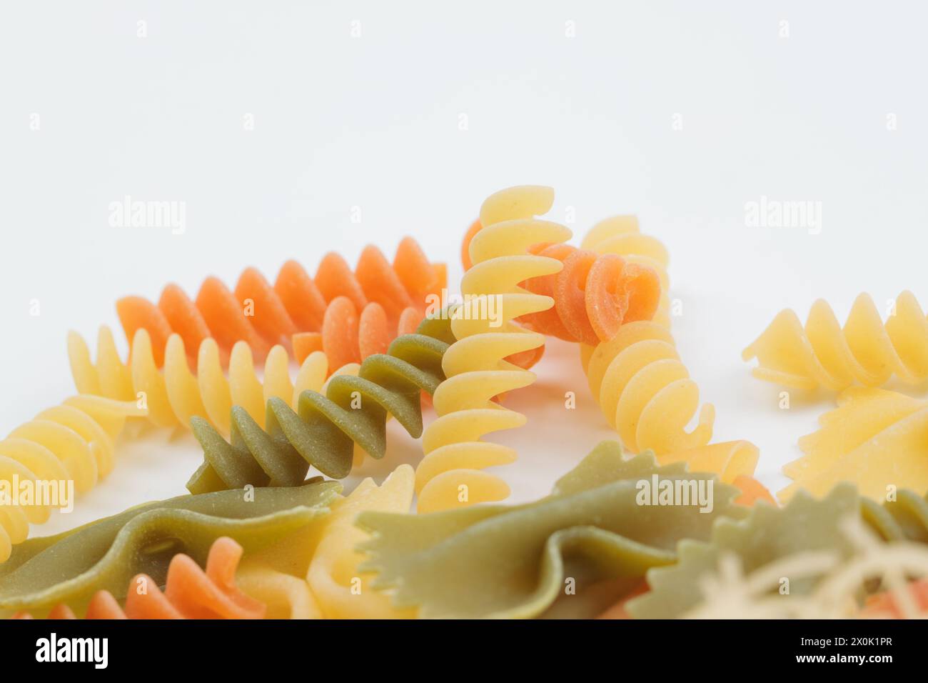 Tricolor macaroni of different types. It is located on a white surface ...
