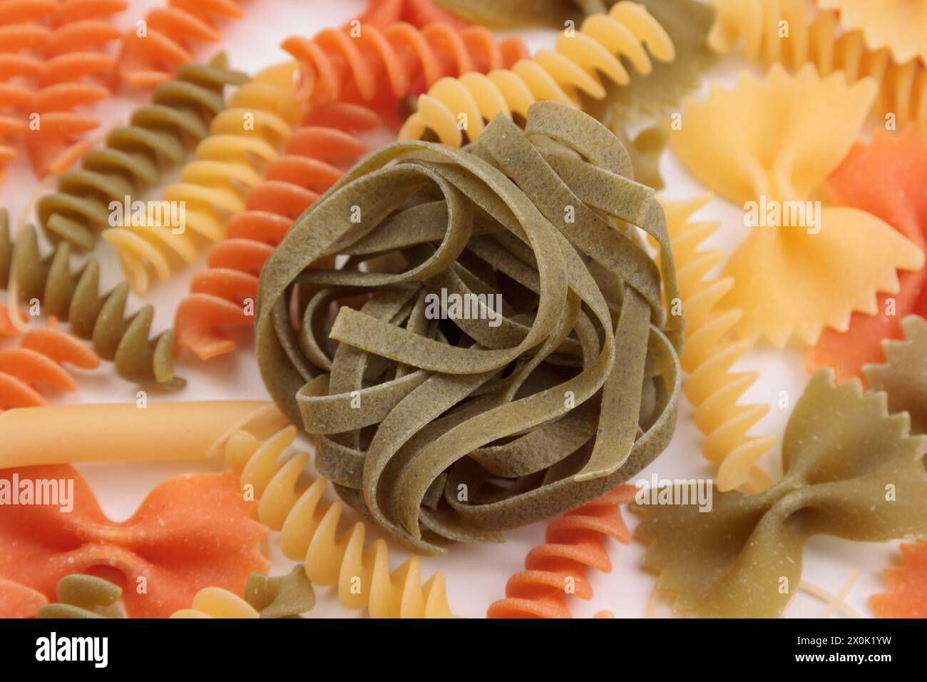 Tricolor macaroni of different types. It is located on a white surface ...