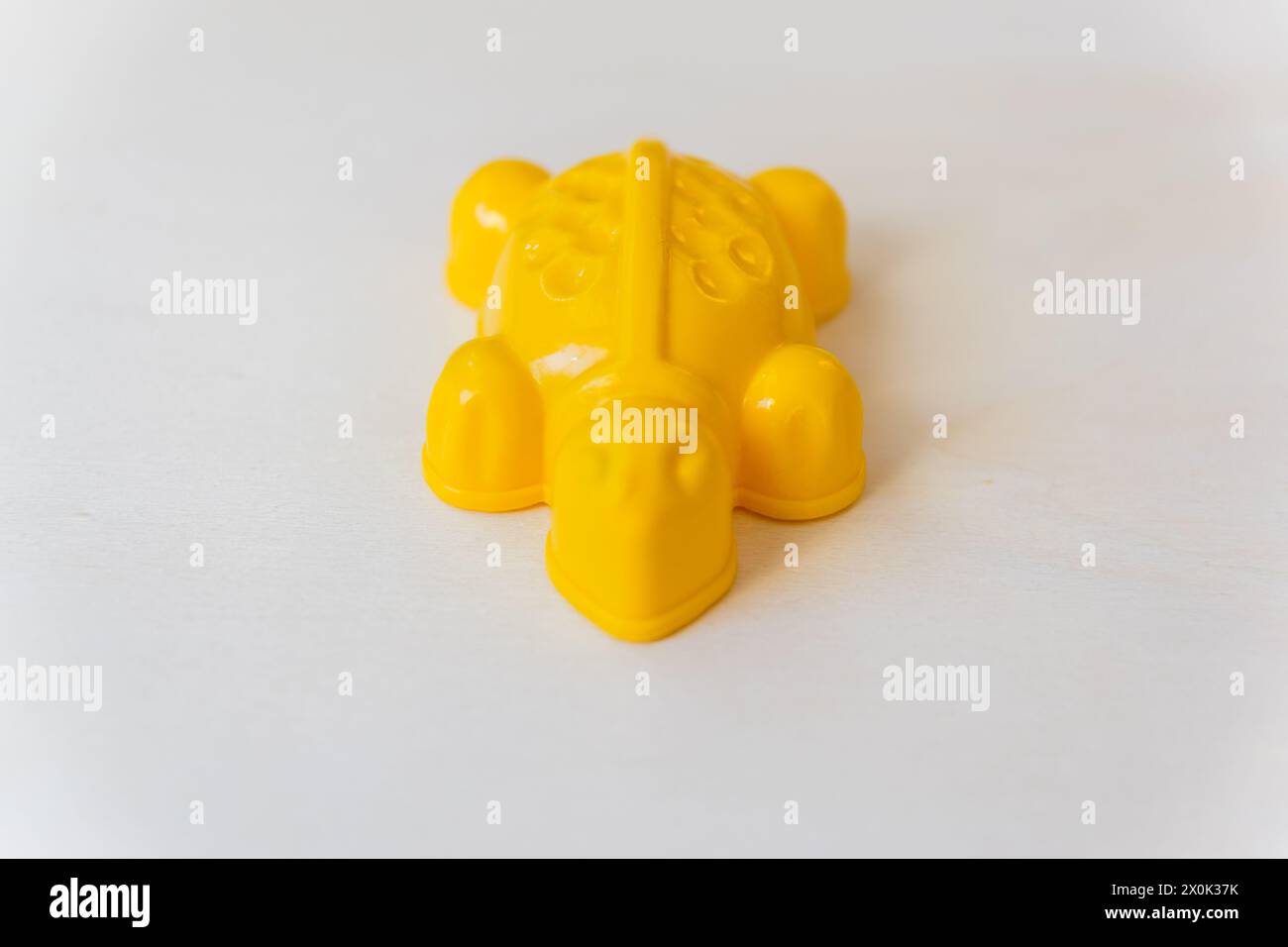 Little toy on the wood background. Yellow plastic turtle on the beige ...