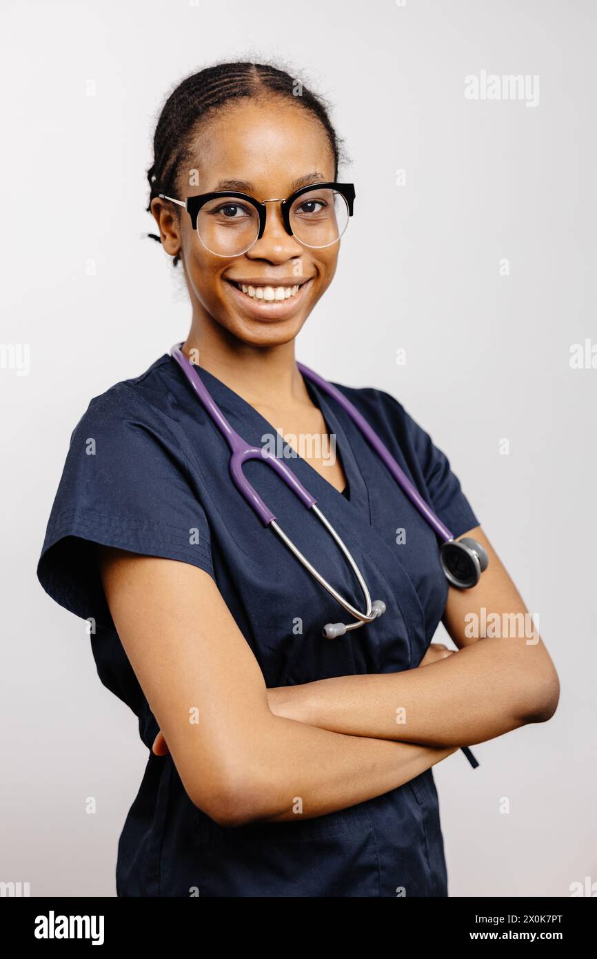A female healthcare worker wearing blue medical scrubs and a ...