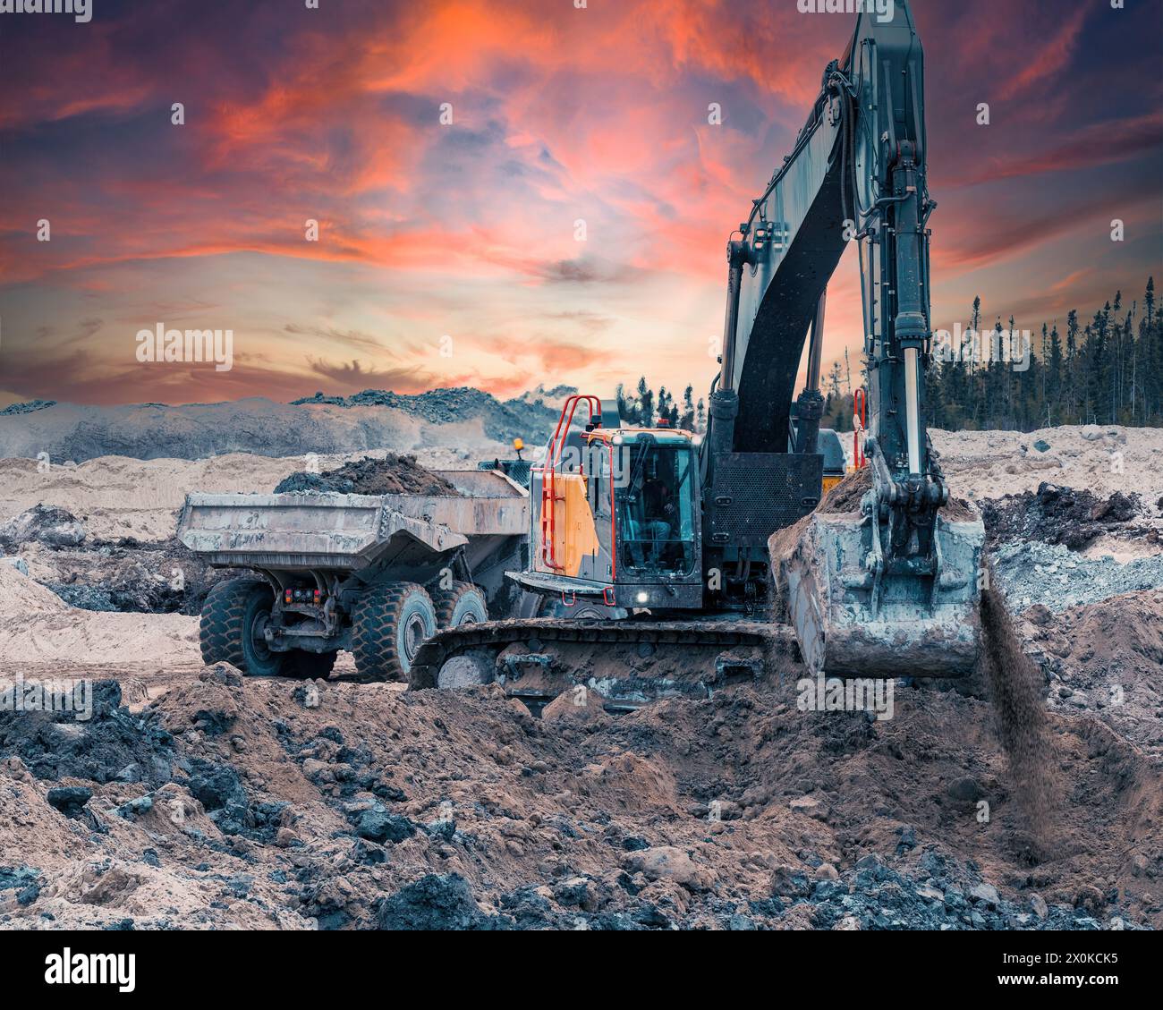 Excavator digging soil on a site at sunset, with a dump truck passing ...
