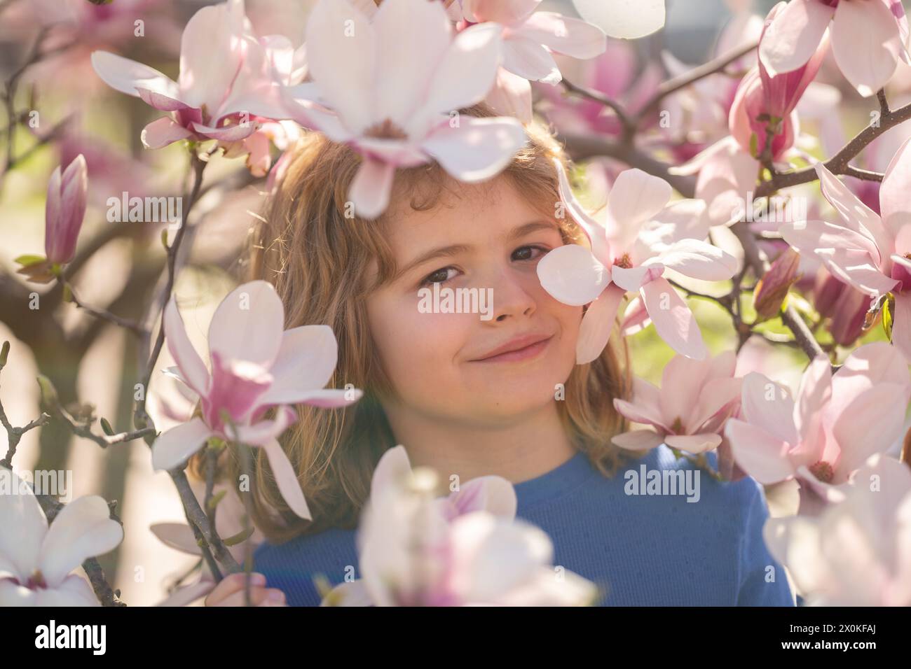 The spring holidays. Happy kid playing under blooming cherry tree with ...