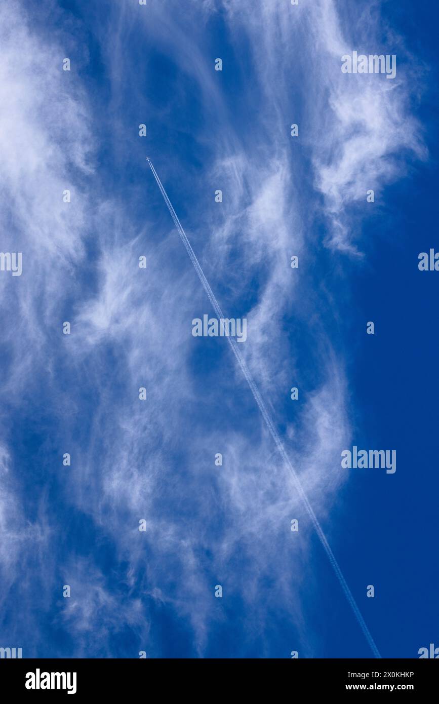 Cirrus clouds ruffled by the wind in the blue sky, contrails of passing ...