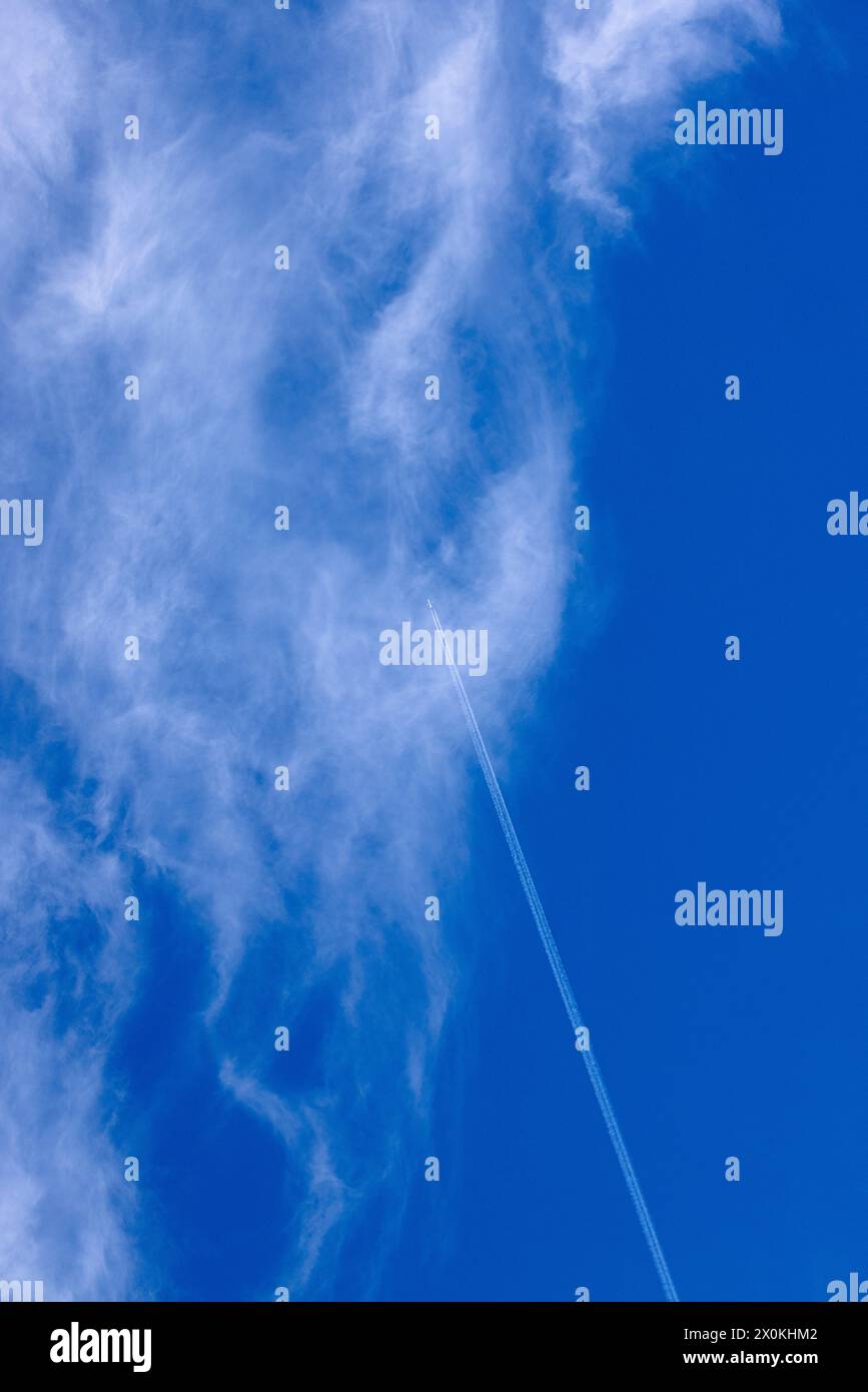 Cirrus clouds ruffled by the wind in the blue sky, contrails of passing ...