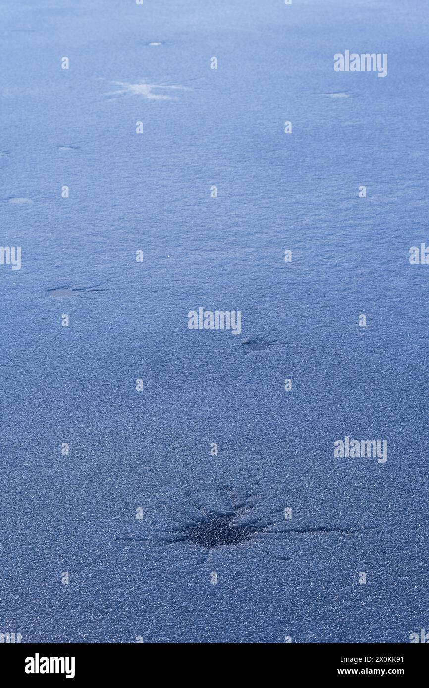 Star-shaped cracks in the ice and fine ice crystals on a frozen lake ...