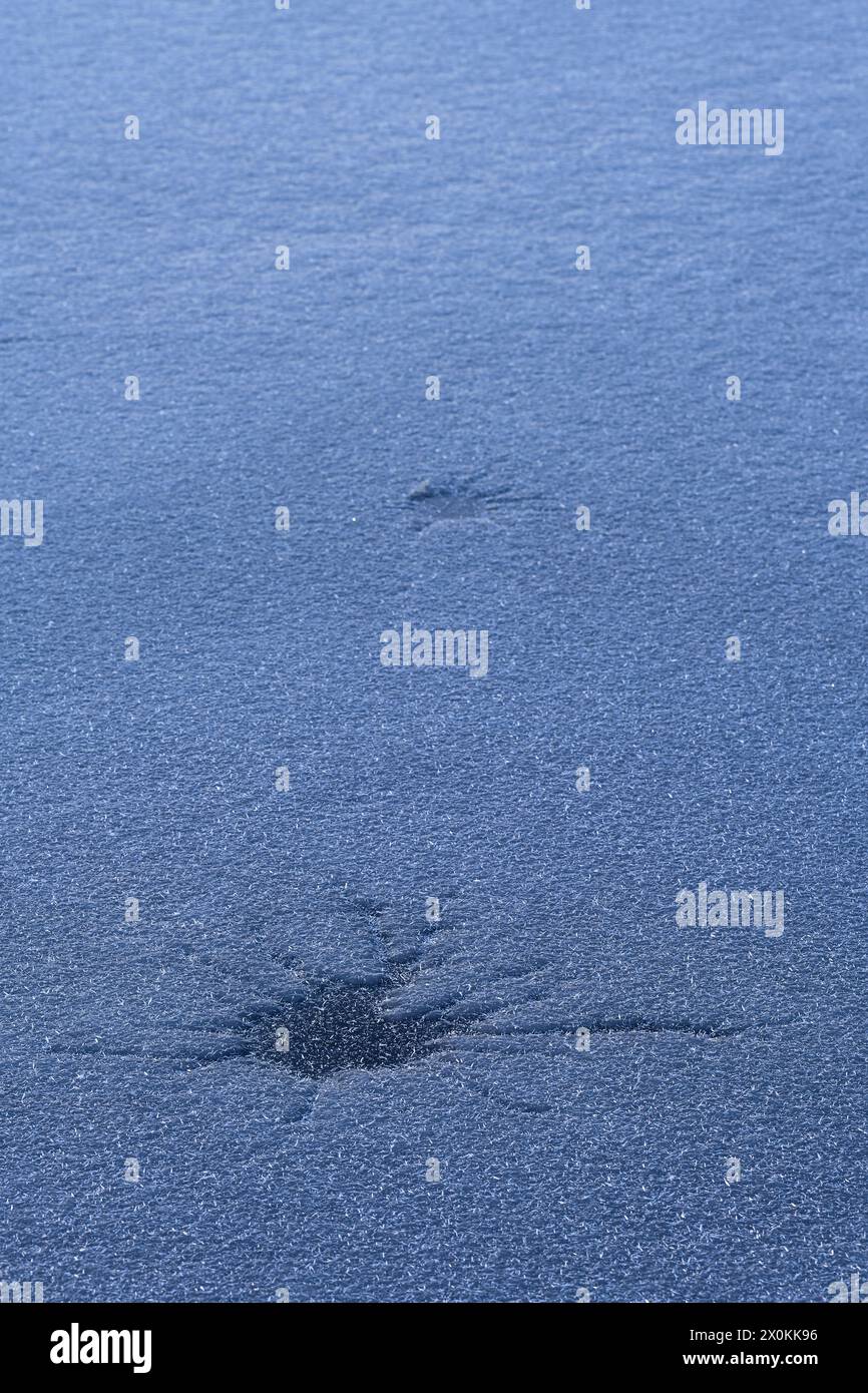 Star-shaped cracks in the ice and fine ice crystals on a frozen lake ...